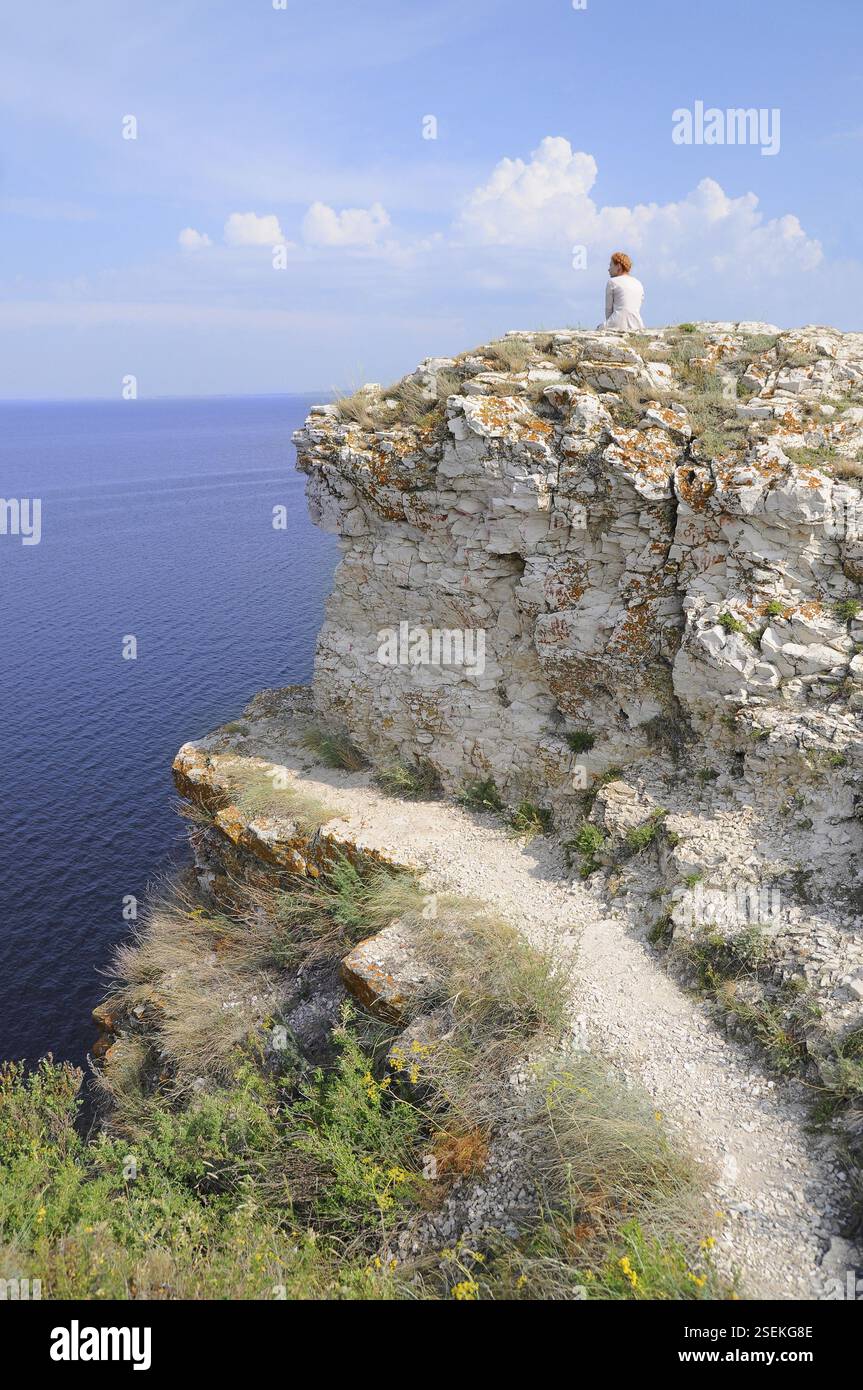 Girl sitting on a rock of Devia hill and observing Volga reservoir in ...