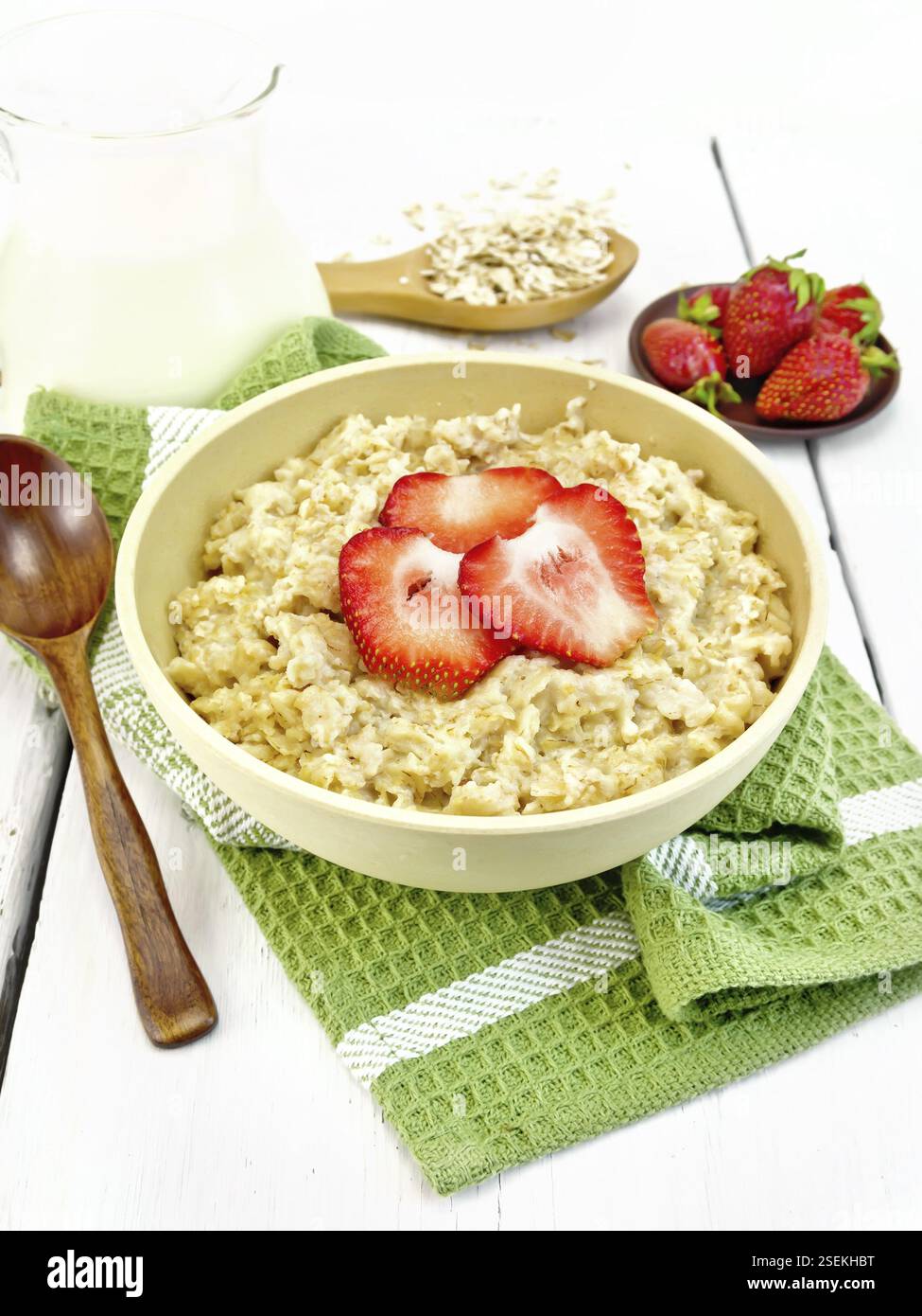 Oatmeal porridge in a bamboo bowl with strawberries on a green napkin ...