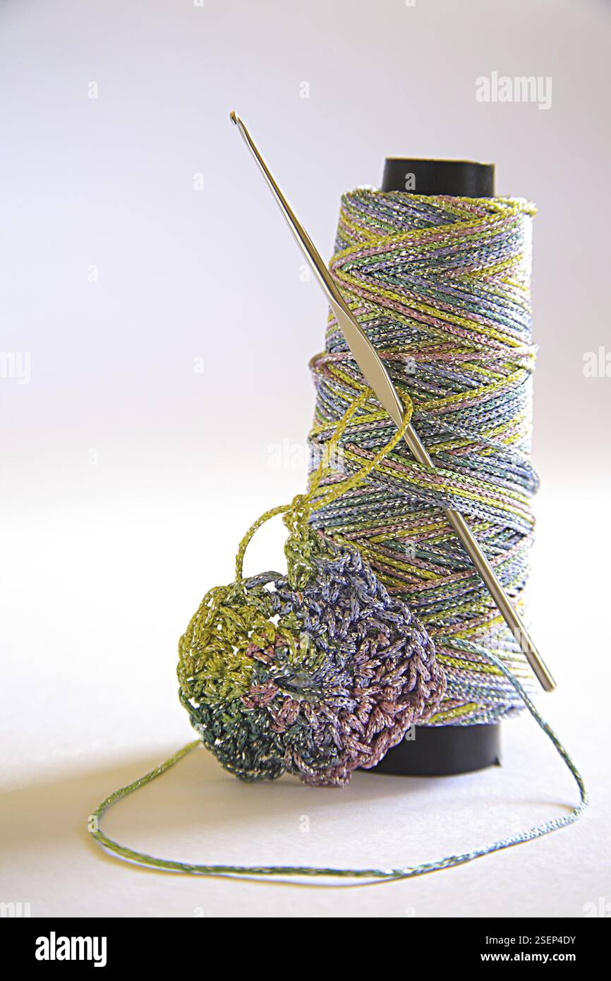 Concept, incomplete silky shiny thread and knitting hooked needle on ...
