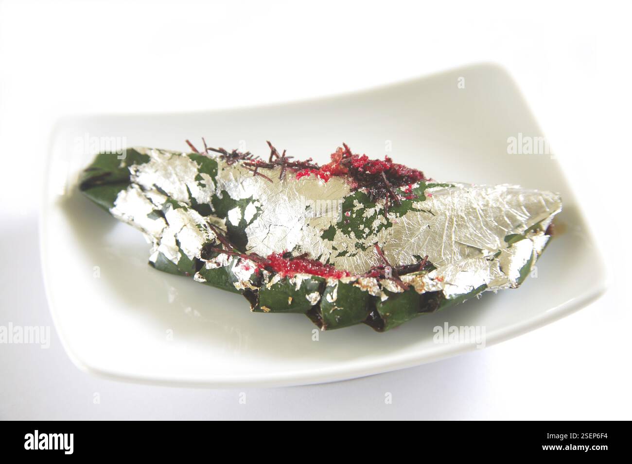 Gilouri pan prepared and folded in betel leaves serve in plate on white ...