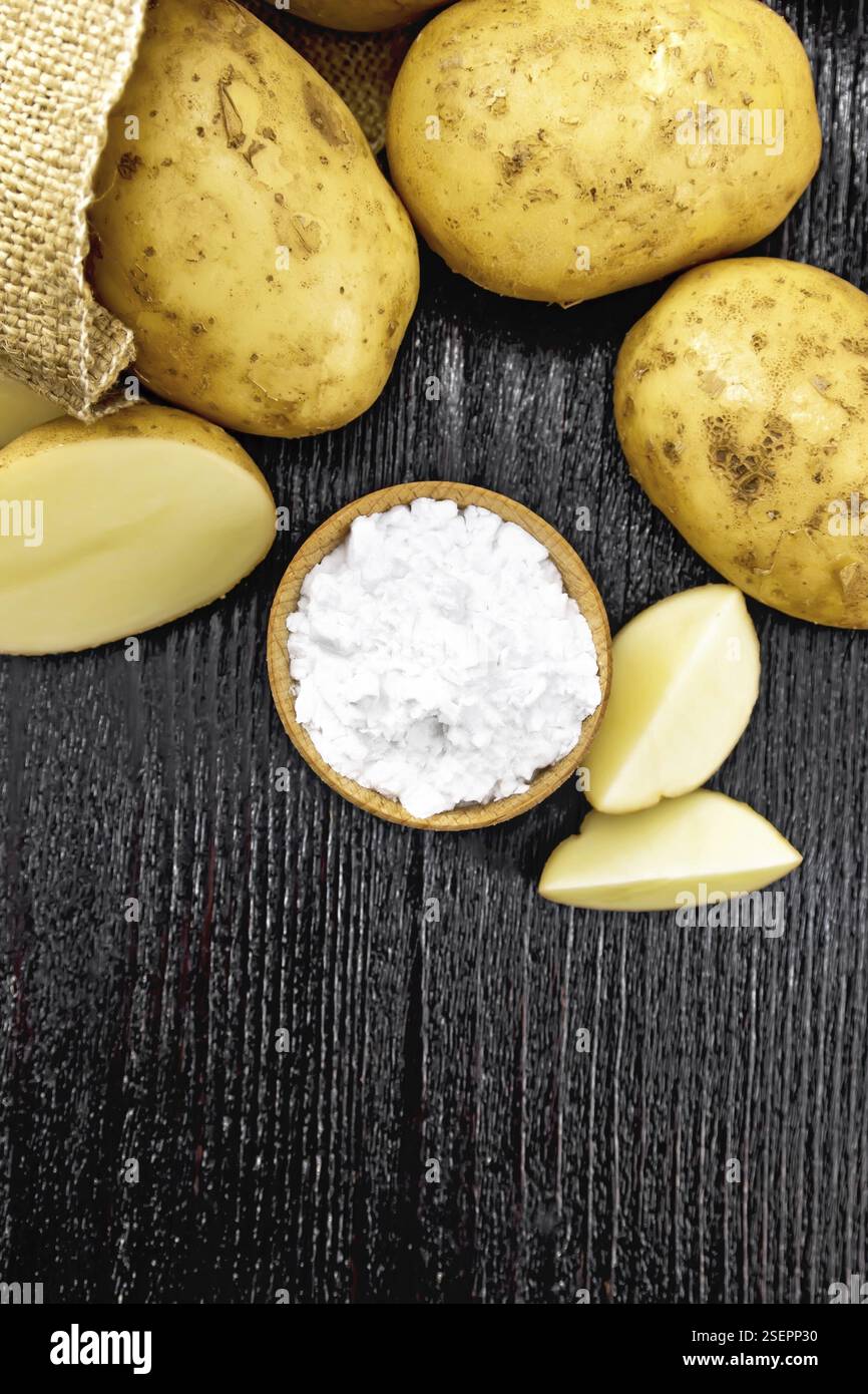 Potato starch in bowl, vegetable tubers in a bag and on a table against ...