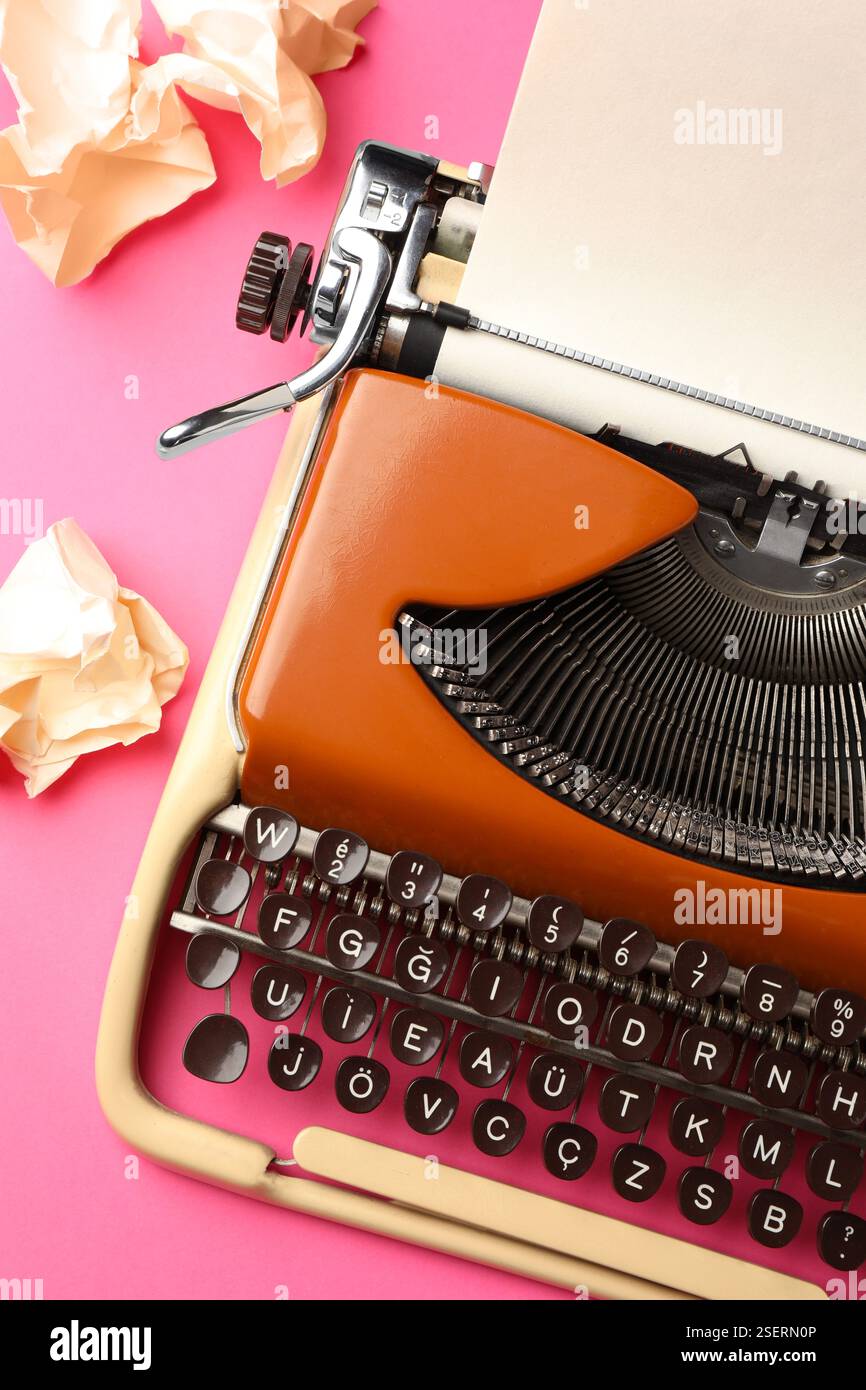 Vintage typewriter and crumpled paper on pink background, top view ...