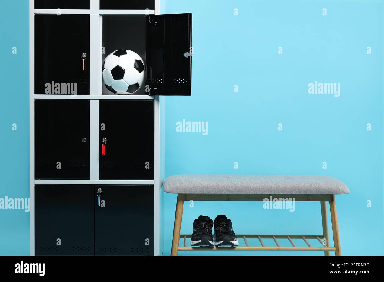 Open locker with soccer ball, bench and sneakers on light blue ...