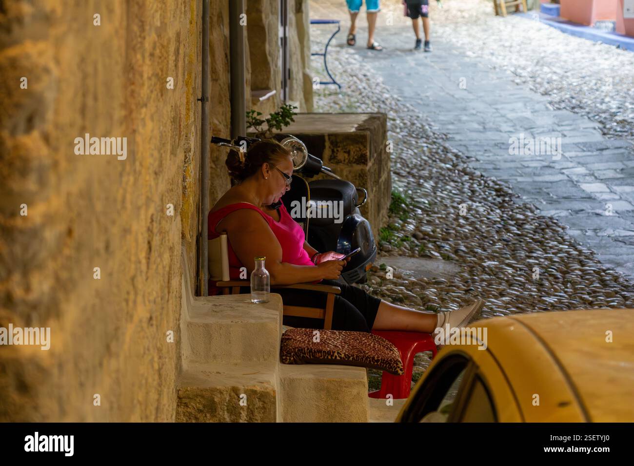 Rhodes, Greece - August 20 2024; Middle-aged woman sitting outside her ...