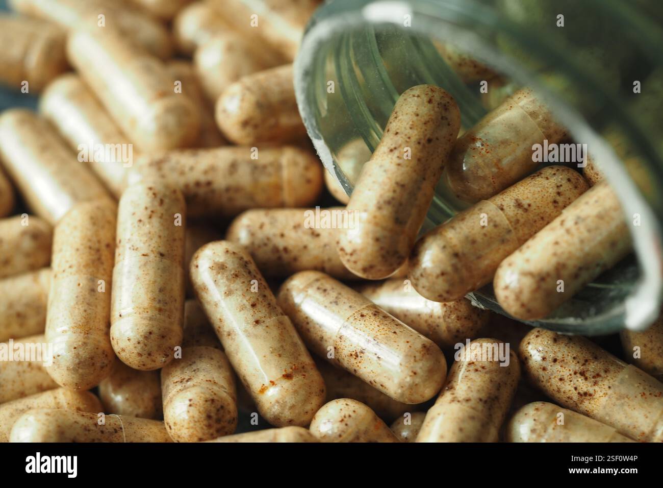 Capsules spilled from a glass container on a textured surface Stock ...