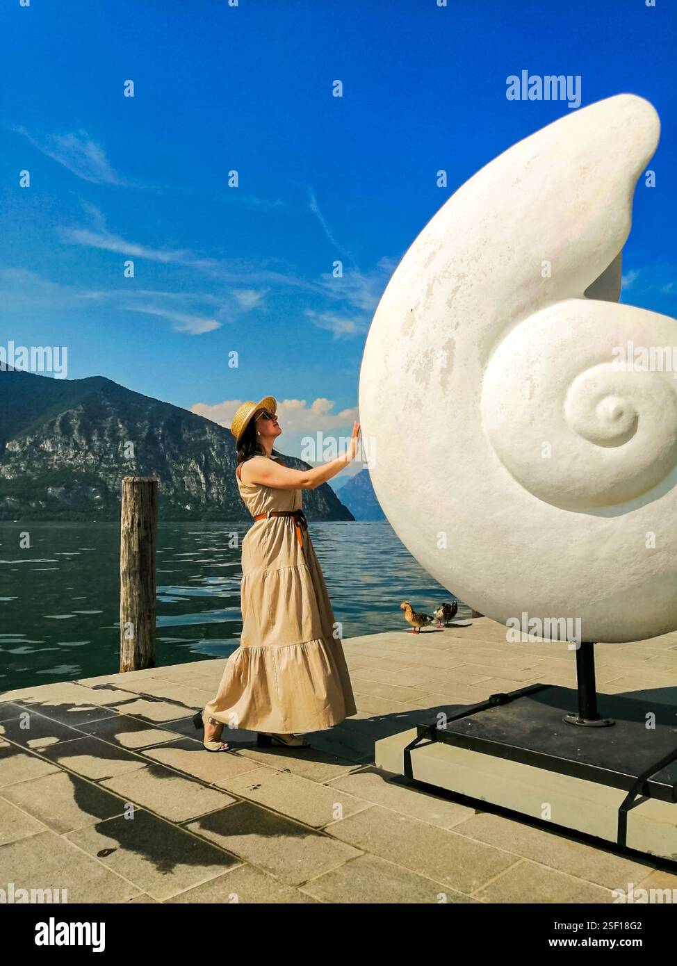 Abstract White Snail Shell Sculpture on a Stone Dock by a Calm Lake ...