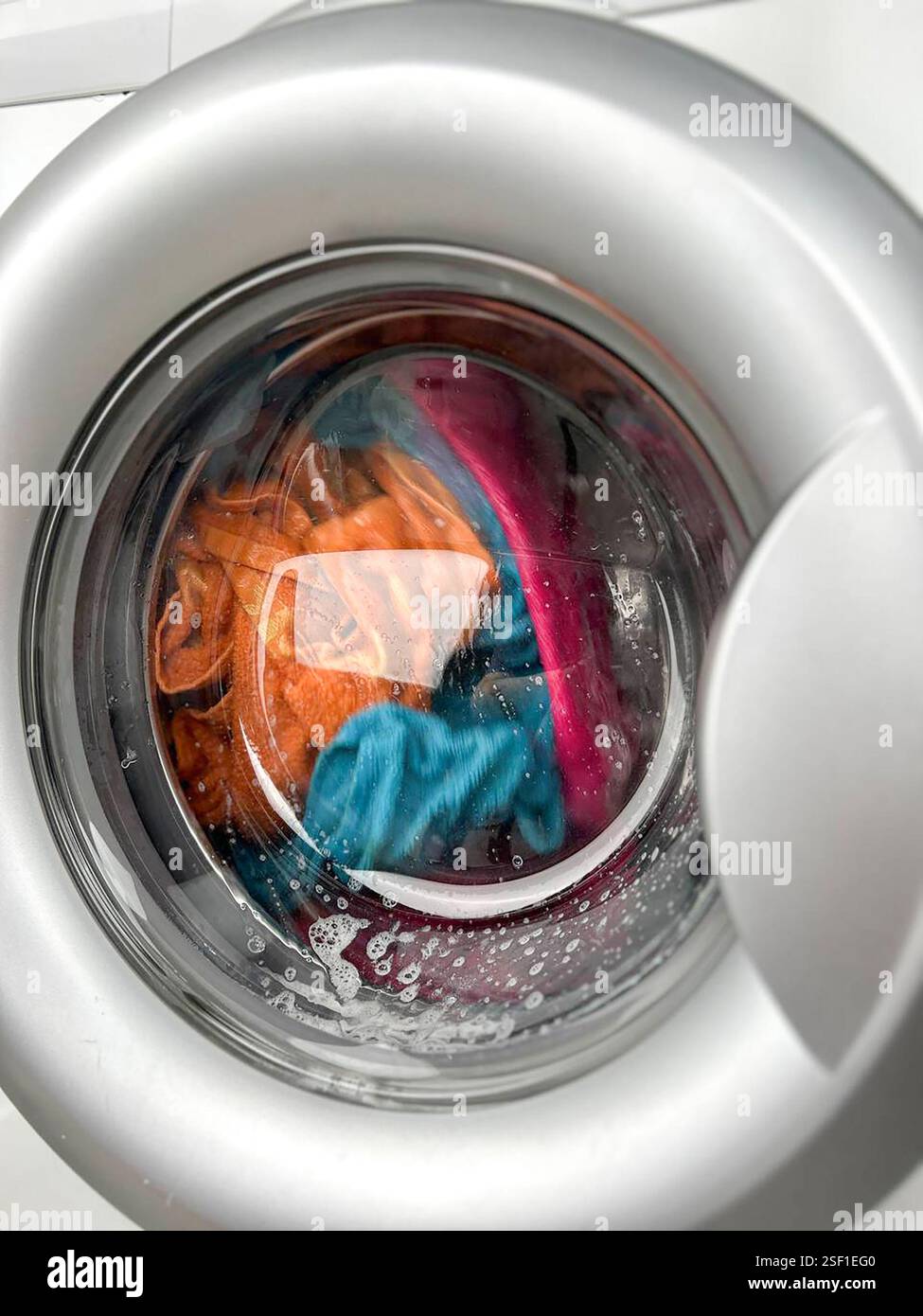 A woman's hand throws a laundry capsule into the washing machine Stock ...