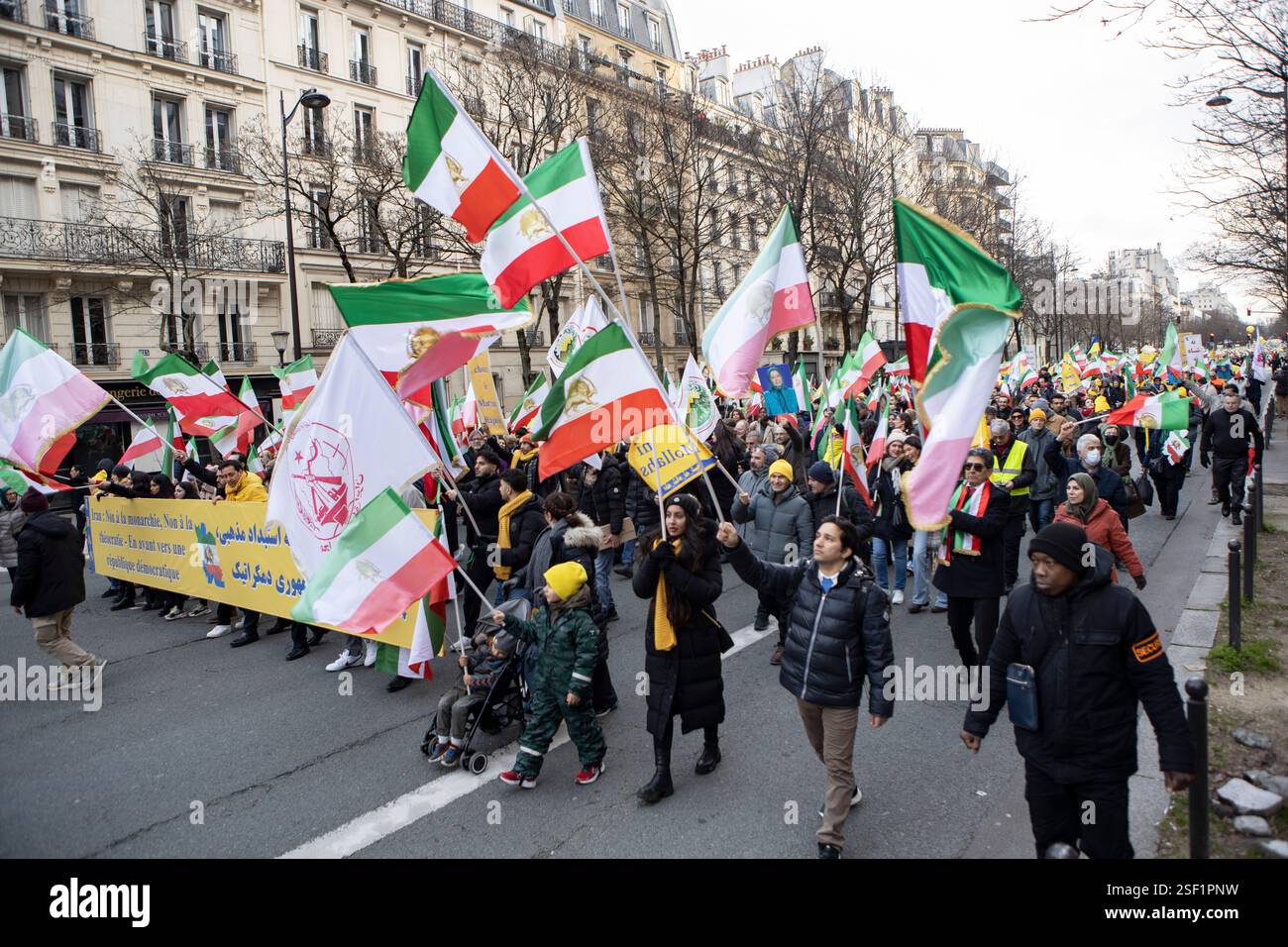 A large crowd of demonstrators marches down a Parisian street, waving ...