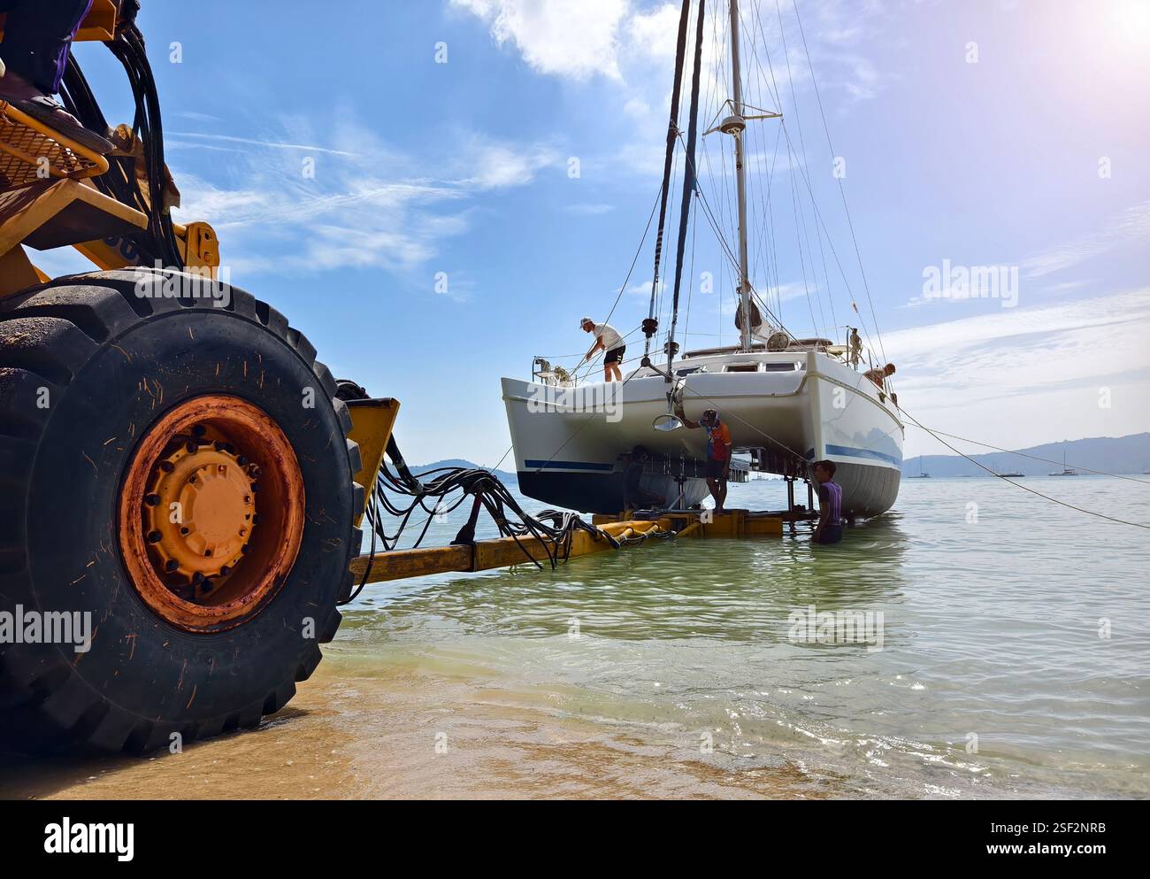 Yellow tractor is pulling a boat out of the water in a beautiful ...