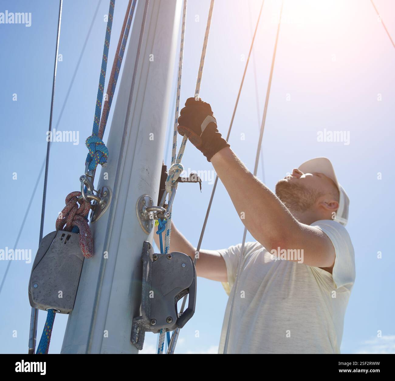 Male captain on deck of sailboat opening sails pulling the rope Stock ...