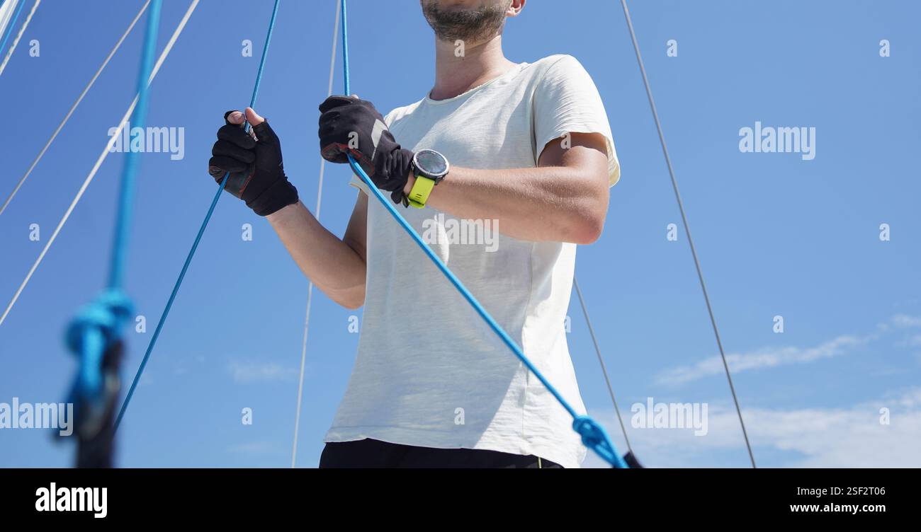 Male captain on deck of sailboat opening sails pulling the rope Stock ...