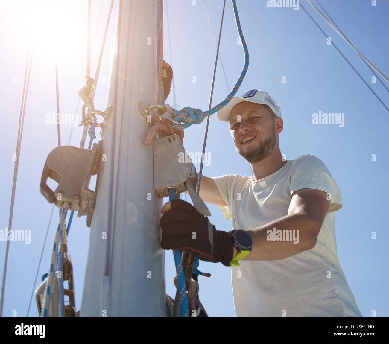 Male captain on deck of sailboat opening sails pulling the rope Stock ...