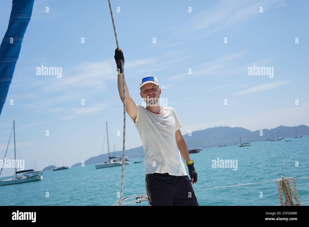 Male captain on deck of sailboat opening sails pulling the rope Stock ...