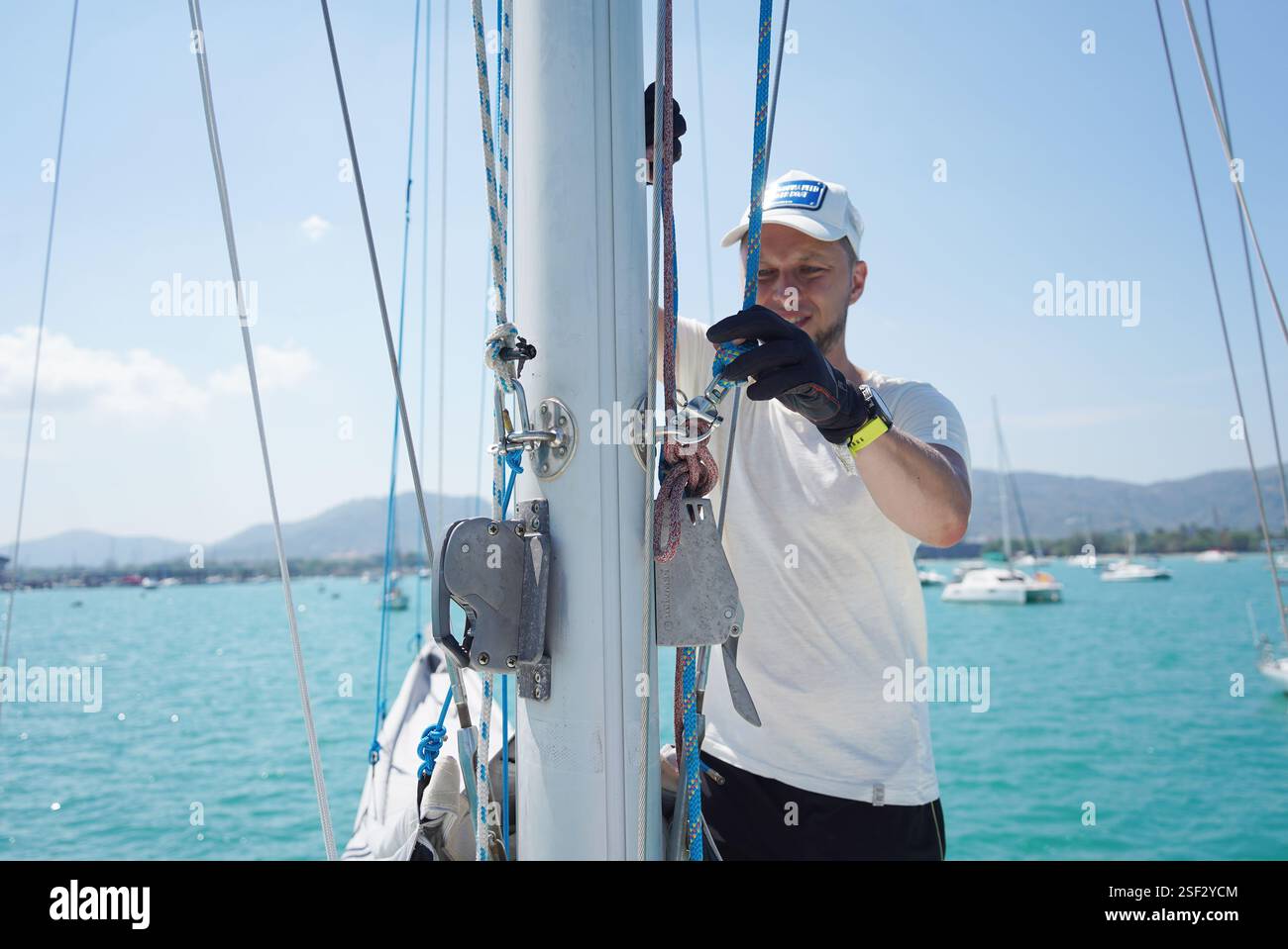 Male captain on deck of sailboat opening sails pulling the rope Stock ...