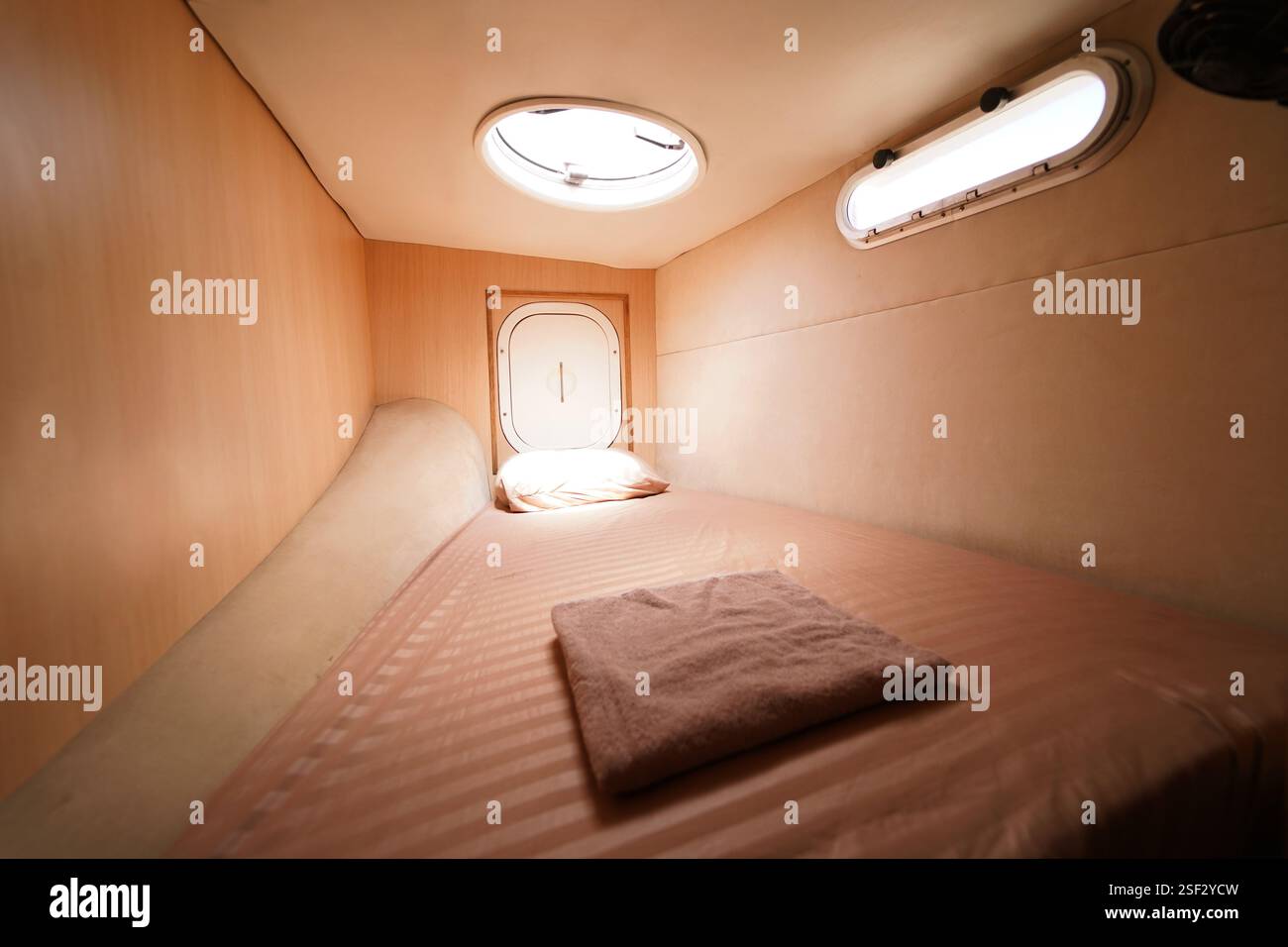 Cozy bed on a voyage boat with a window overhead with natural light ...