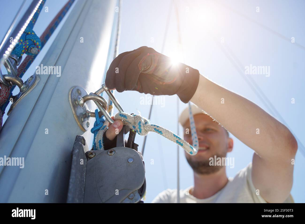 Male captain on deck of sailboat opening sails pulling the rope Stock ...