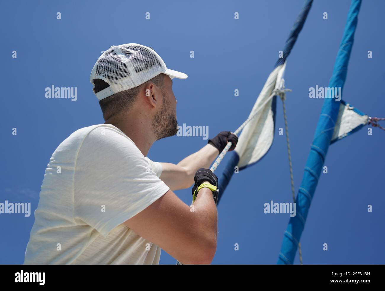 Male captain on deck of sailboat opening sails pulling the rope Stock ...