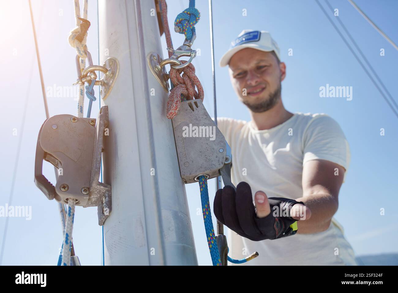 Male captain on deck of sailboat opening sails pulling the rope Stock ...