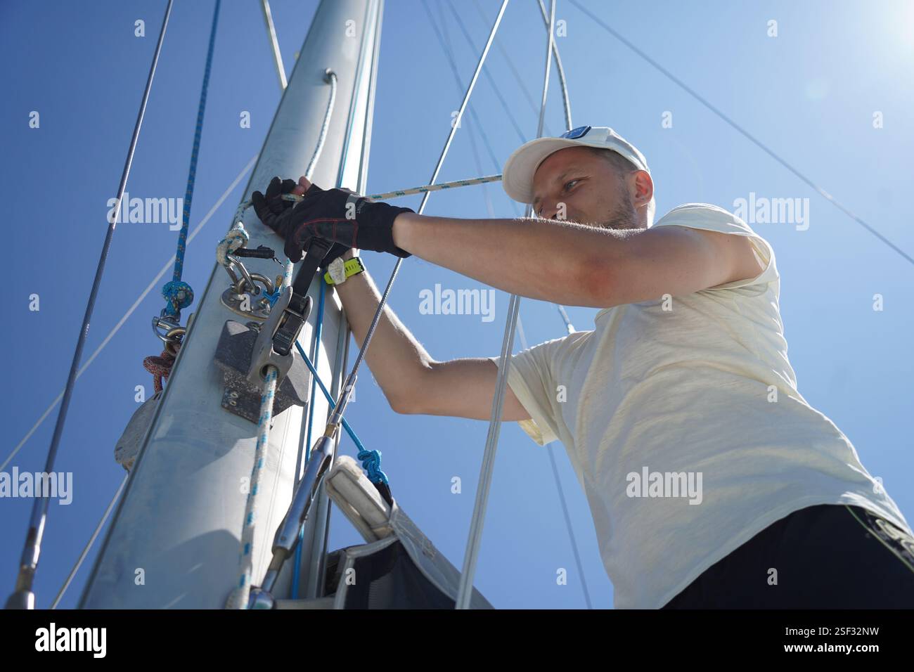 Male captain on deck of sailboat opening sails pulling the rope Stock ...