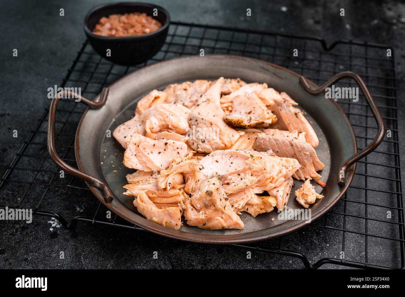 Roast salmon fillet, pulled fish meat on a steel tray. black background ...