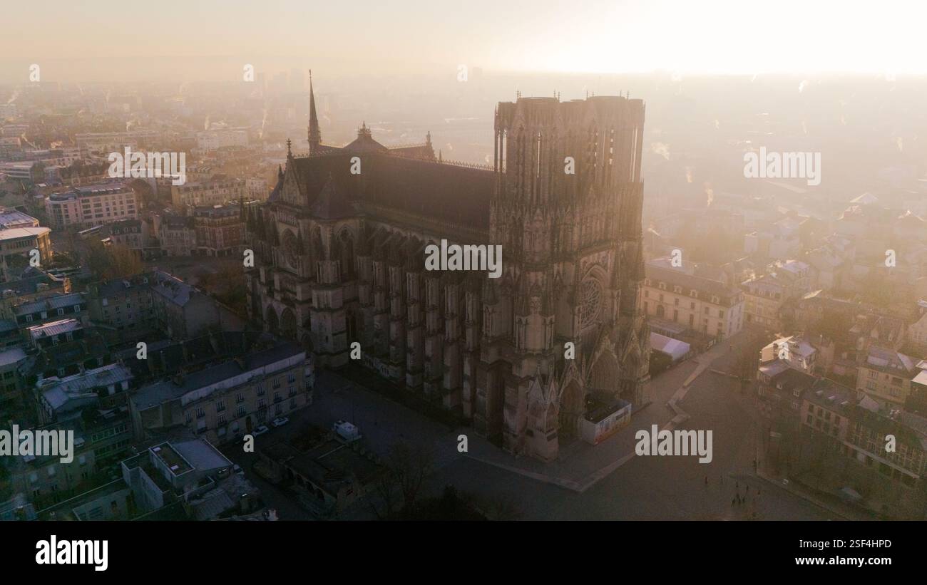 Aerial view of Reims Cathedral during sunrise, bathed in golden light ...