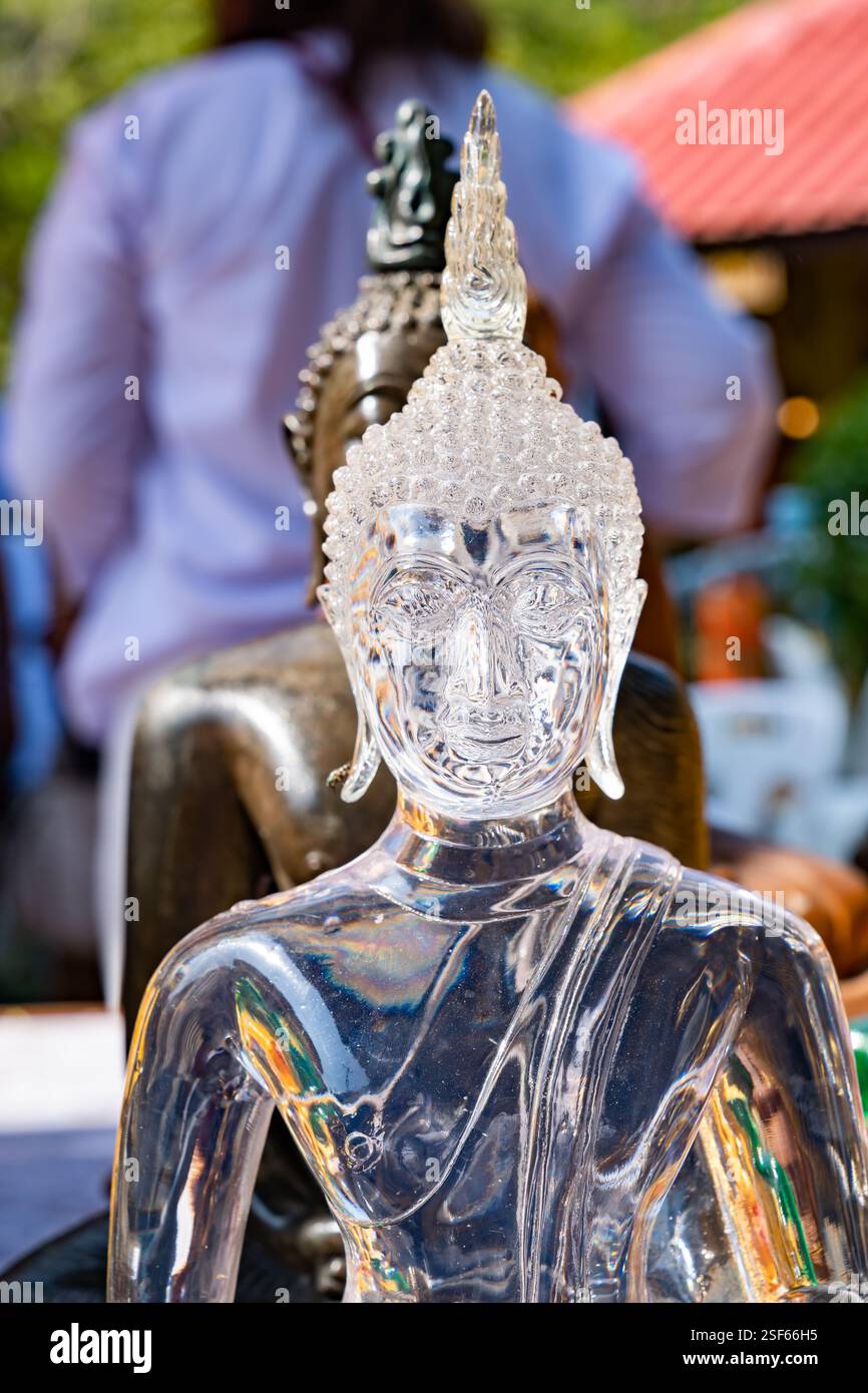 Transparent glass buddha statue in meditation posture among various ...