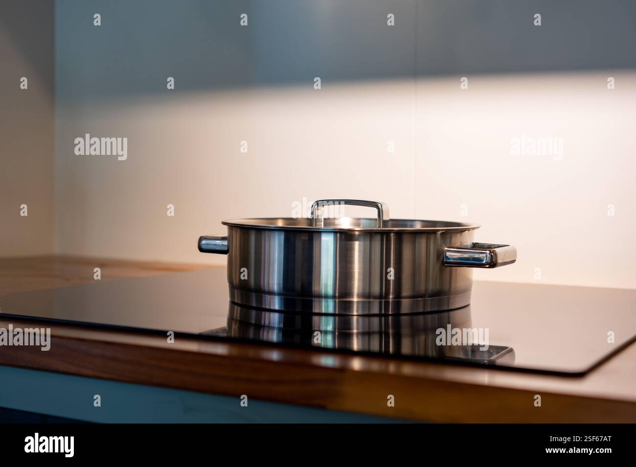 stainless steel pot on electronic modern flat stove in low light on ...