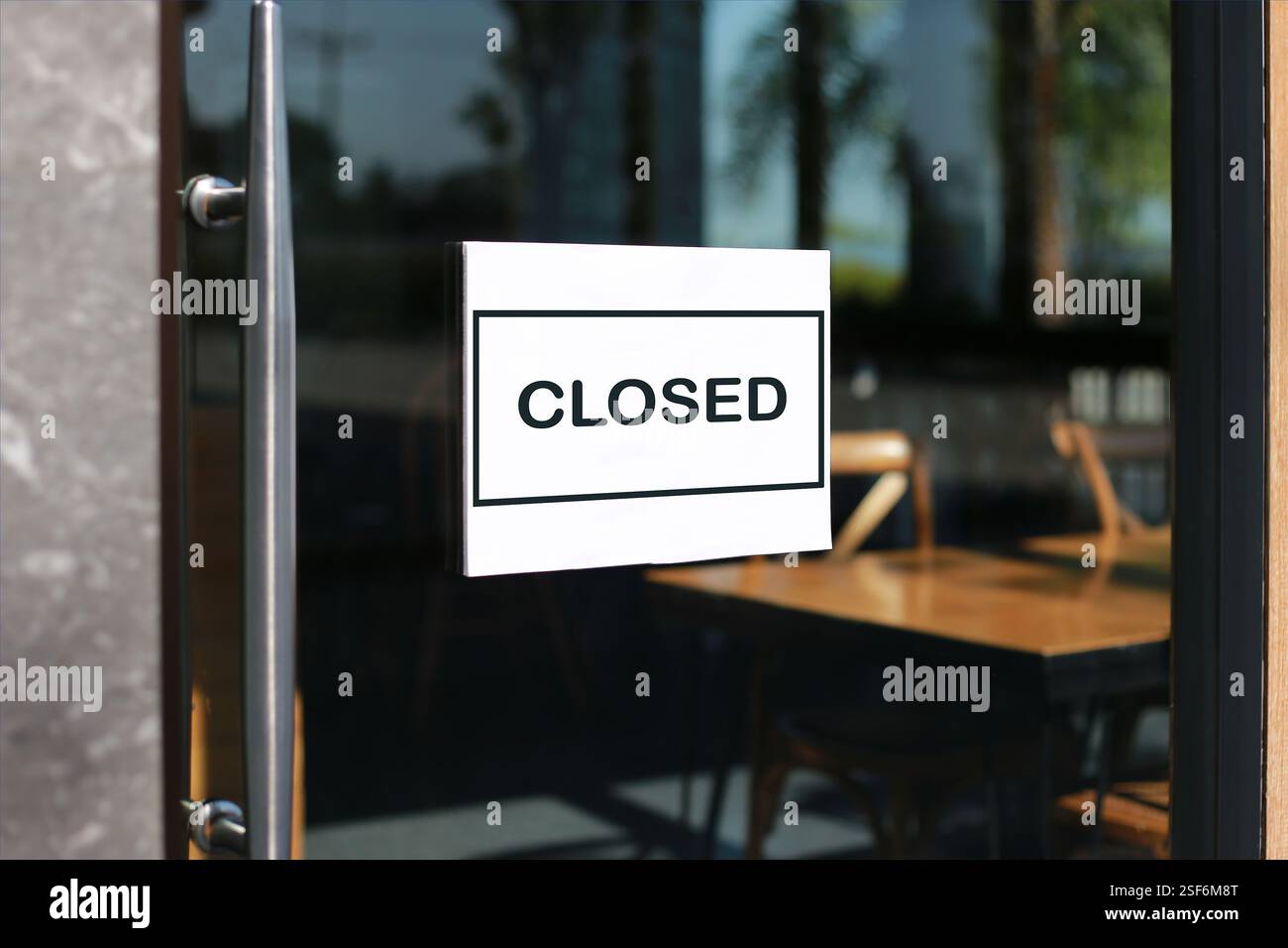 Closed sign on the glass door in front of the store Stock Photo - Alamy