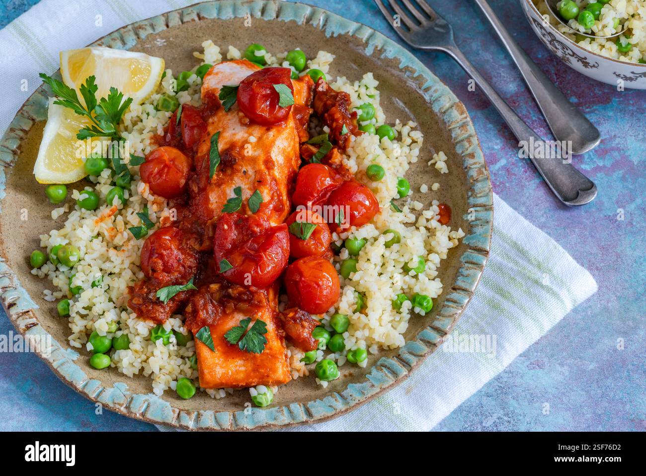 Harissa salmon with bulgur wheat, cherry tomatoes and green peas Stock ...