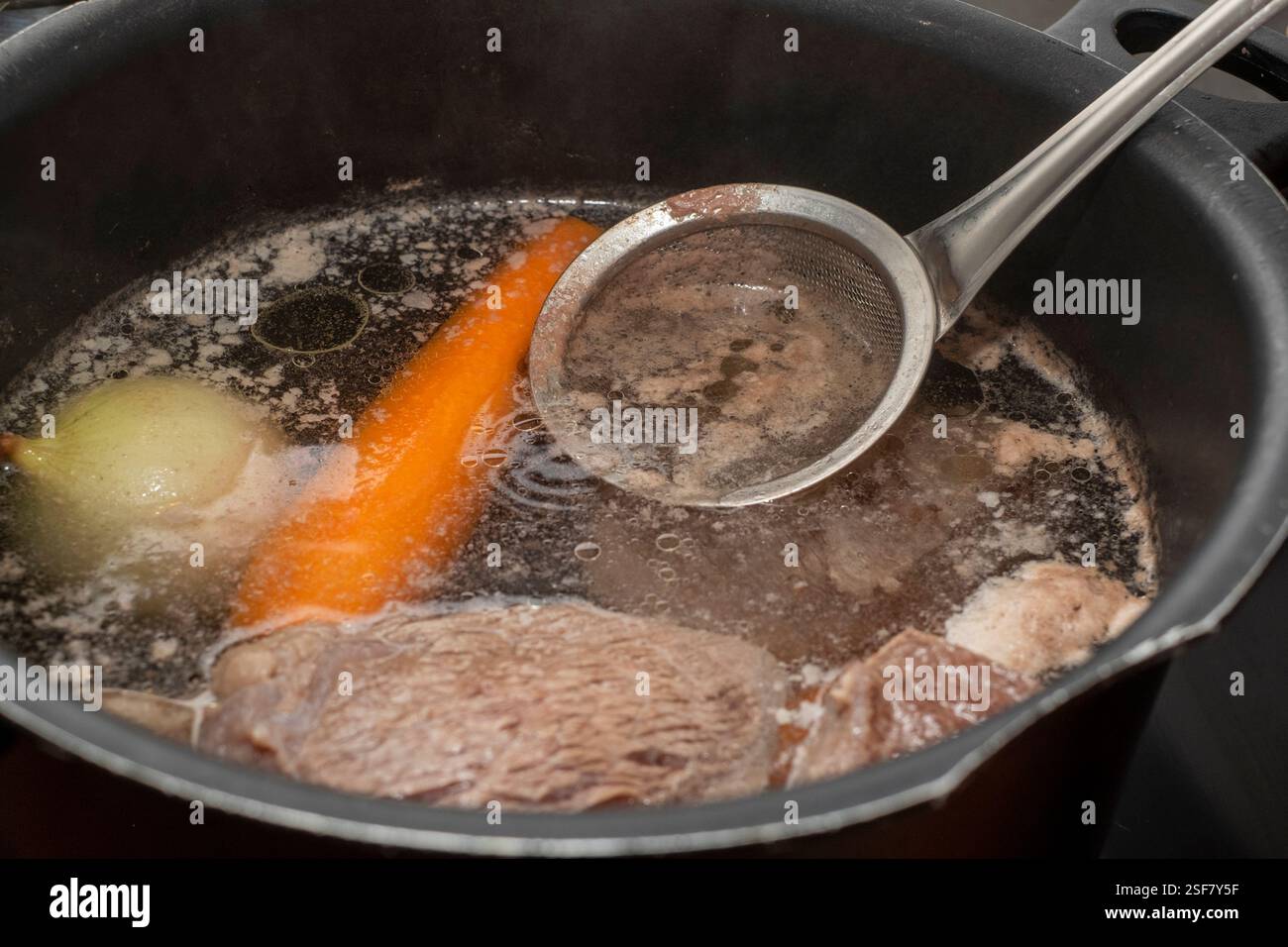 a broth foam and ladle in a boiling soup, studio closeup Stock Photo ...