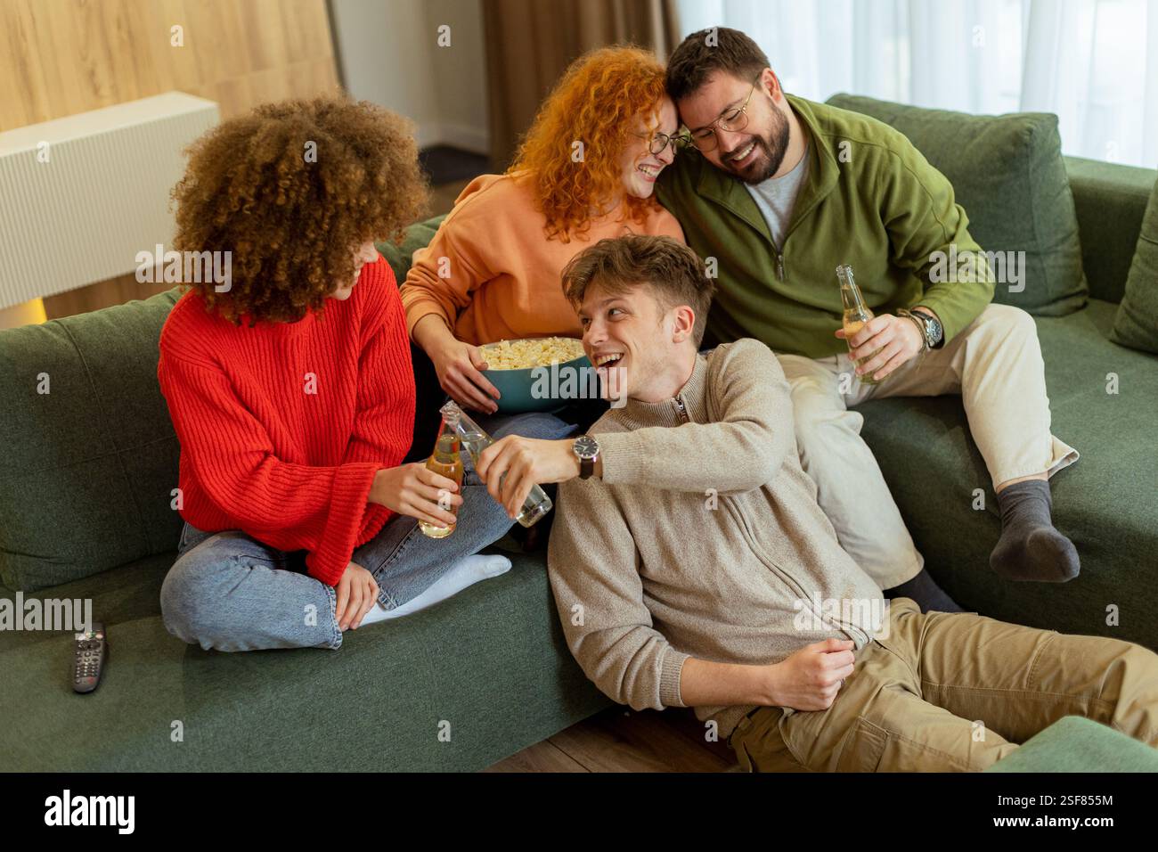 Laughter fills a well-lit living room as four friends share a joyful ...