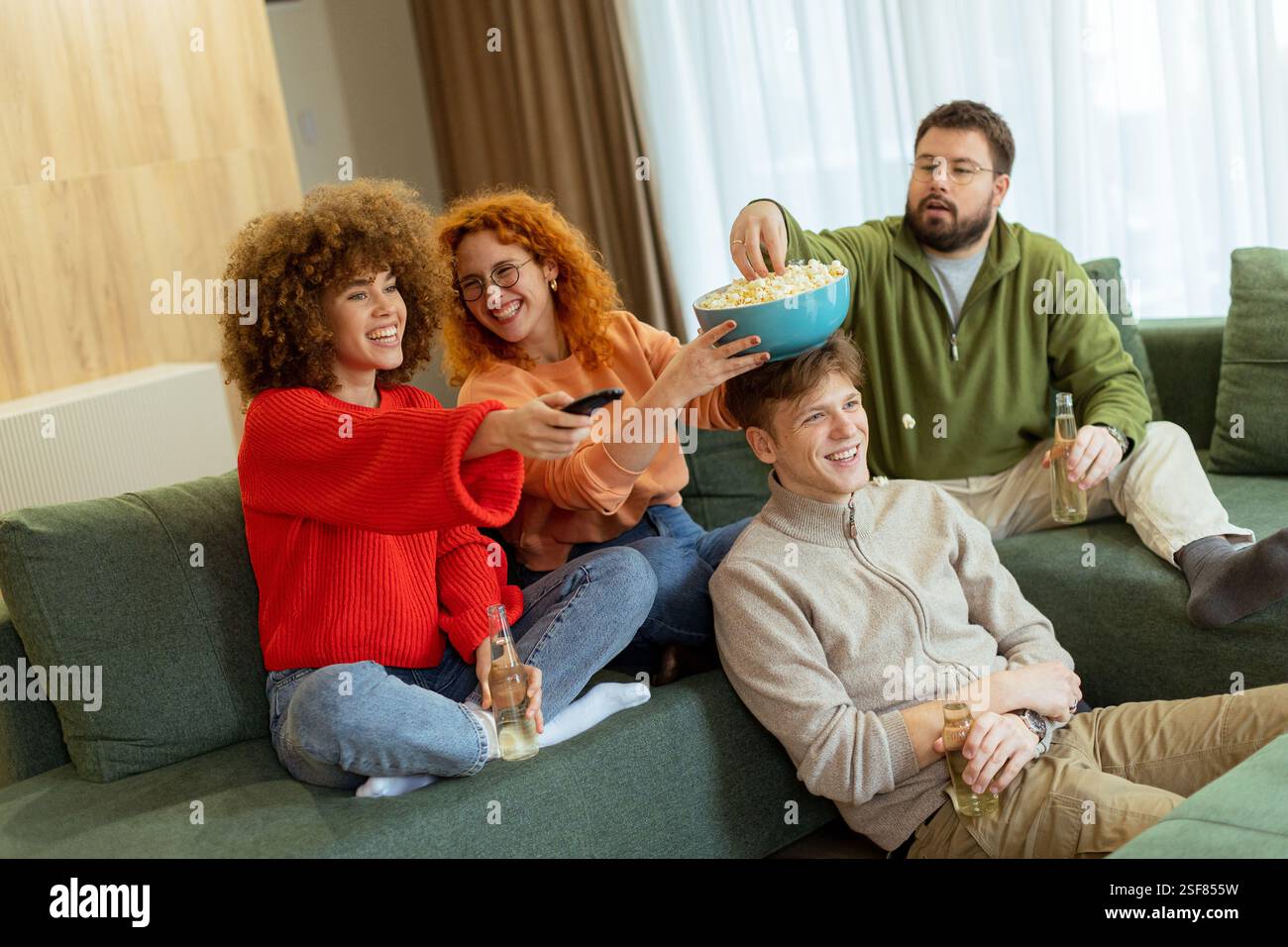 Four friends gather in a warm, inviting living room, sharing laughter ...