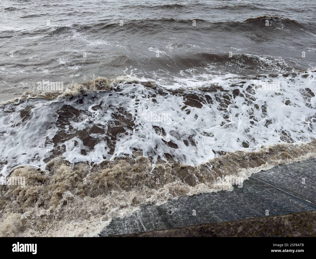Waves breaking on incoming tide against sea wall Stock Photo - Alamy