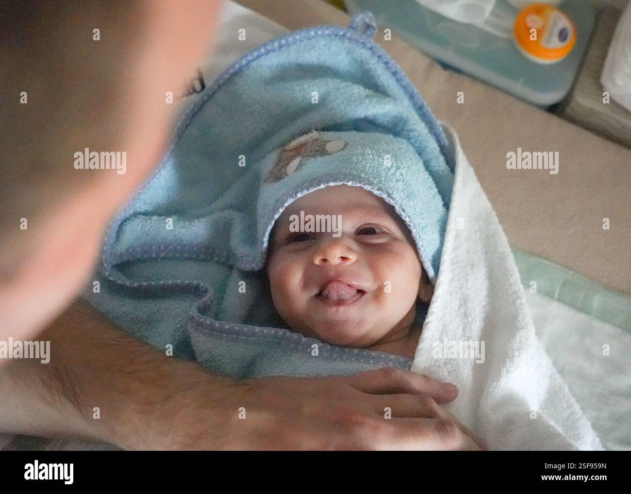 the baby's contented face after bathing, wrapped in a towel and showing ...