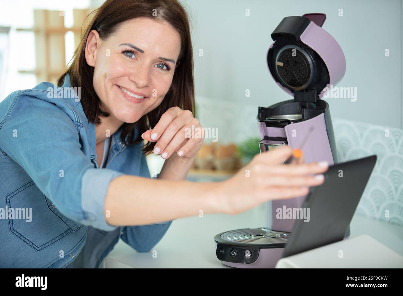 woman checking tablet on how to fix a coffee machine Stock Photo - Alamy