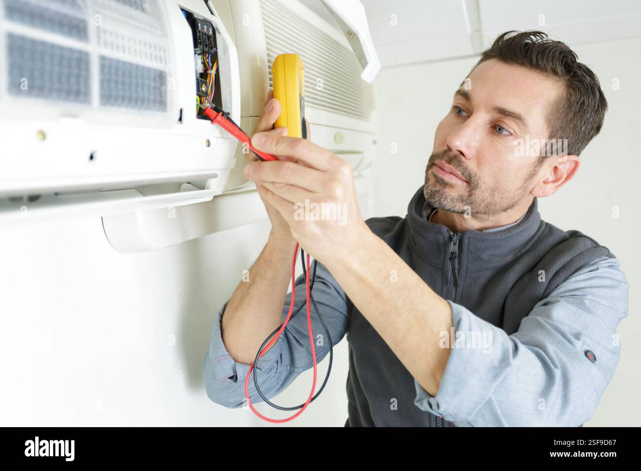 male electrician checking air conditioner with digital multimeter Stock ...