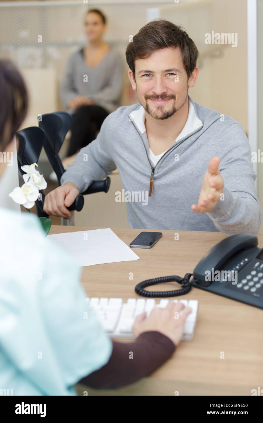 happy male patient registering at hospital reception desk Stock Photo ...