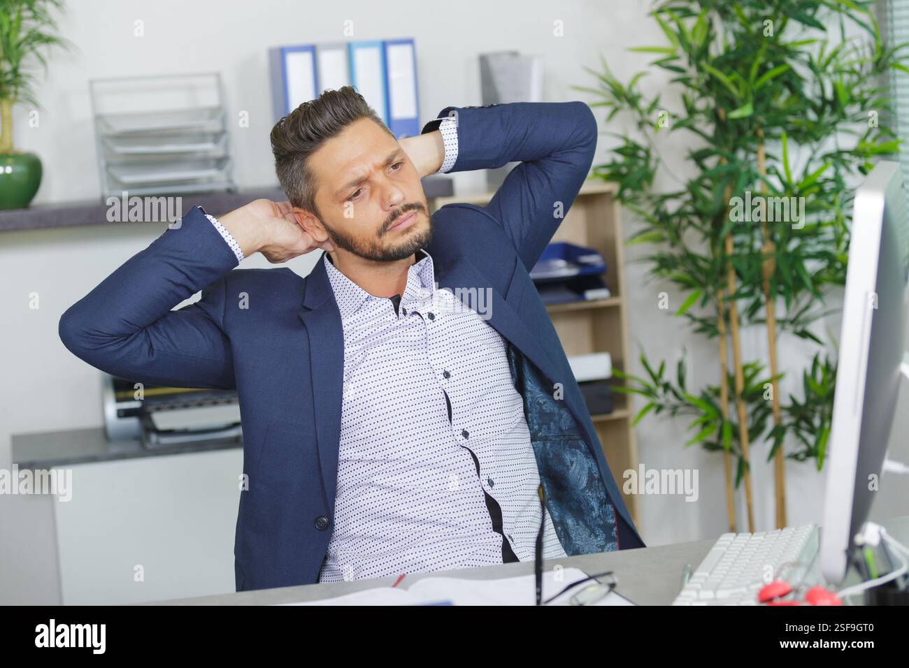 portrait of businessman stretching in office Stock Photo - Alamy
