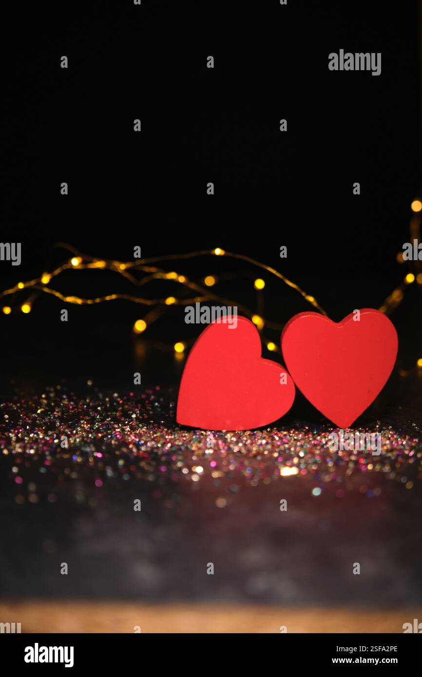 On a dark background in the light of lights, two hearts next to each ...
