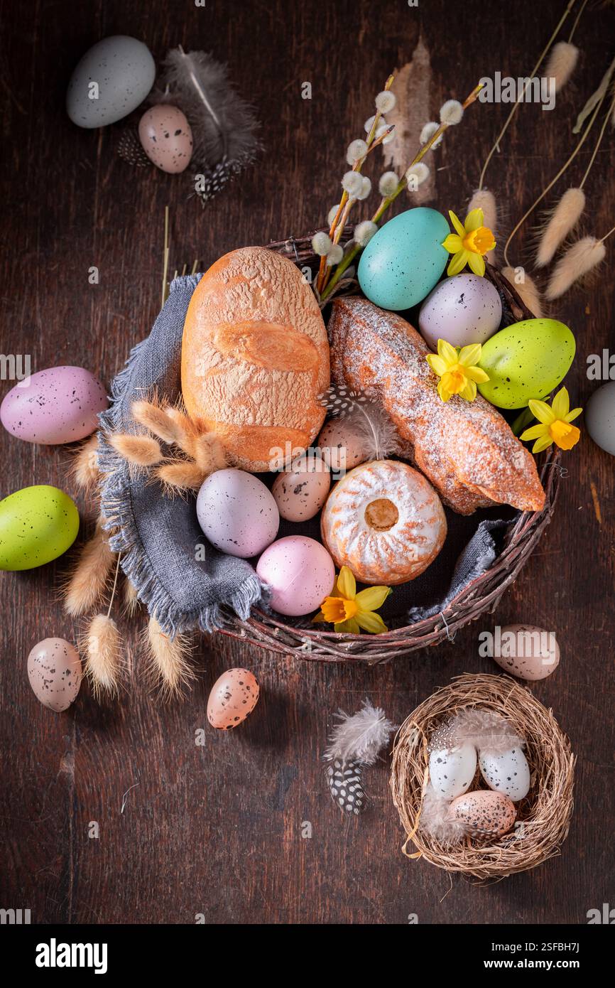 Traditional Easter basket with flowers, painted eggs and bread. Easter ...