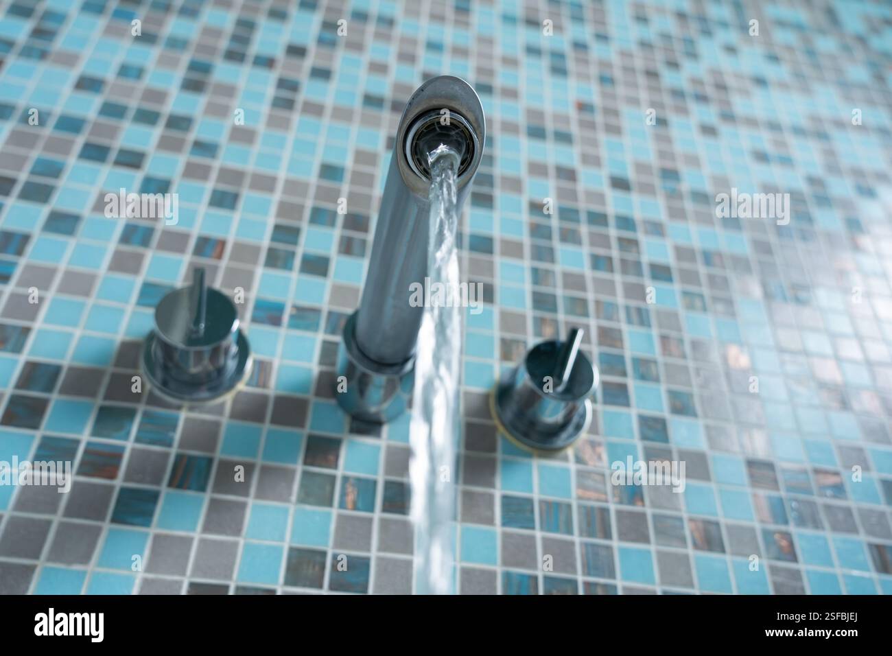 Bathroom mixer tap running water seen from below in an England bathroom ...