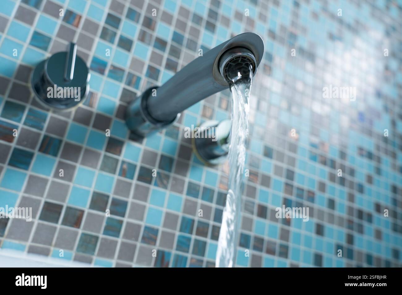 Bathroom mixer tap running water seen from below in an England bathroom ...