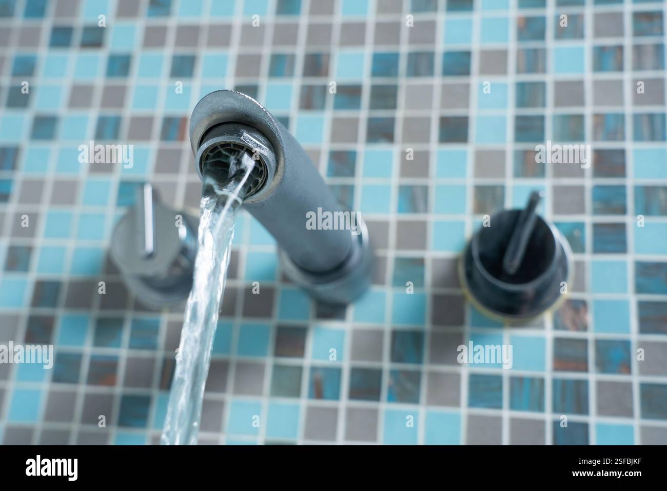 Bathroom mixer tap running water seen from below in an England bathroom ...