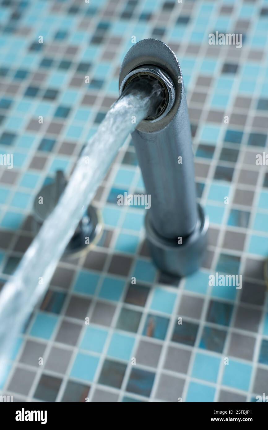 Bathroom mixer tap running water seen from below in an England bathroom ...