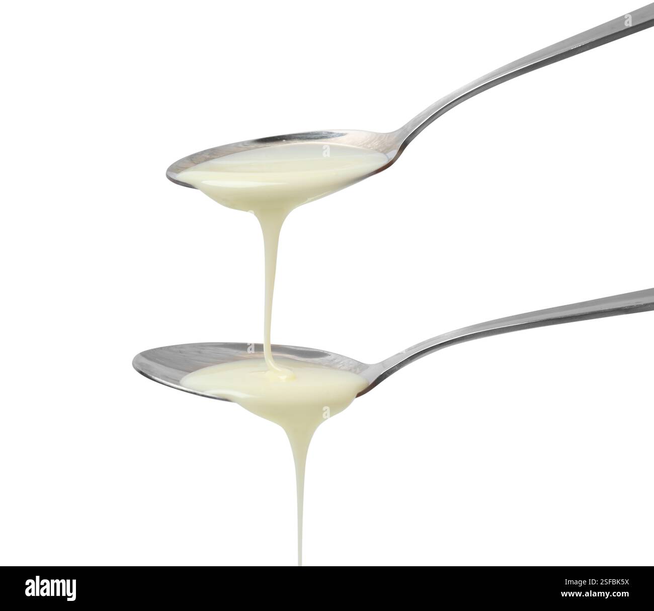 Condensed milk flowing down from spoons isolated on white Stock Photo ...