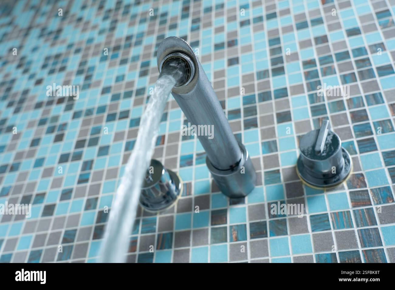 Bathroom mixer tap running water seen from below in an England bathroom ...