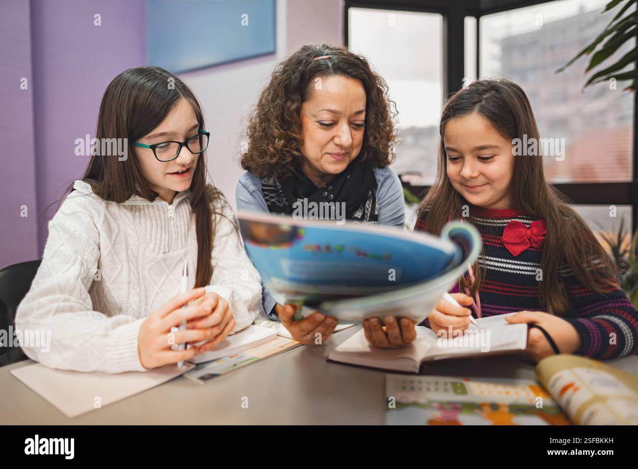 Female teacher helping elementary students at language school class ...