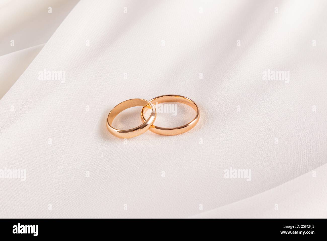 Two charming gold wedding rings on the soft surface of cream-colored ...