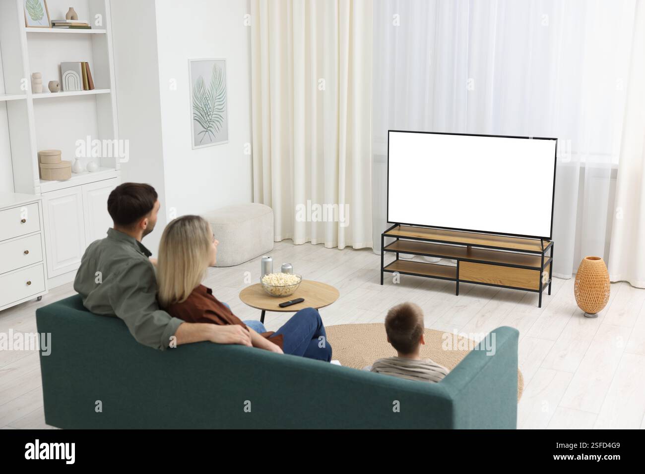 Happy family with snacks and drinks watching tv together at home Stock ...