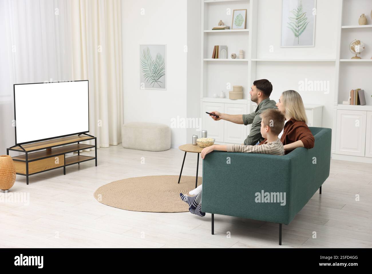 Happy family with snacks and drinks watching tv together at home Stock ...
